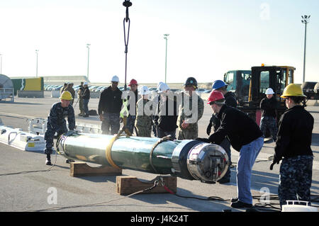 An MK-48 inert training torpedo is guided into the weapon loading skid ...