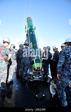 An MK-48 inert training torpedo is guided into the weapon loading skid ...