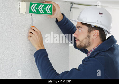 man fixing illuminated exit sign to wall Stock Photo - Alamy