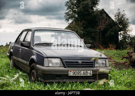 Old rusty sedan car Opel Ascona C parking in green grass on old wooden house background Stock ...