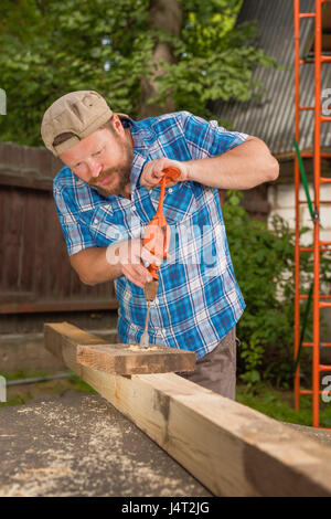 Carpenter drilling wooden plank on table, closeup Stock Photo - Alamy