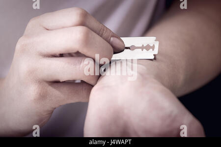 Suicide attempt of a hand with a razor blade Stock Photo - Alamy