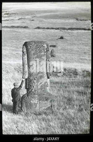 View of a back of moai with a man standing on the left of the sculpture ...