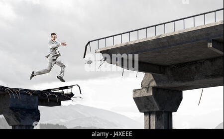 Businessman jumping over a gap in the bridge as a symbol of bridge ...