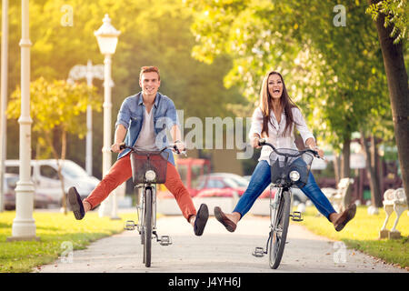 happy funny young couple riding on bicycle Stock Photo - Alamy