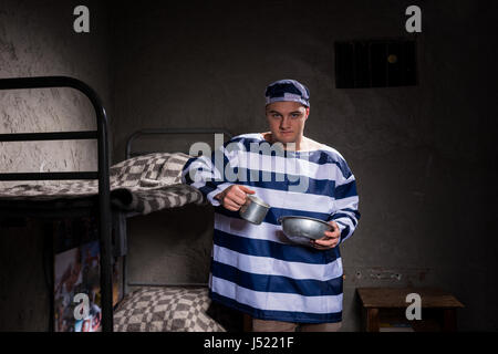 Angry male prisoner wearing prison uniform with sewed number standing ...