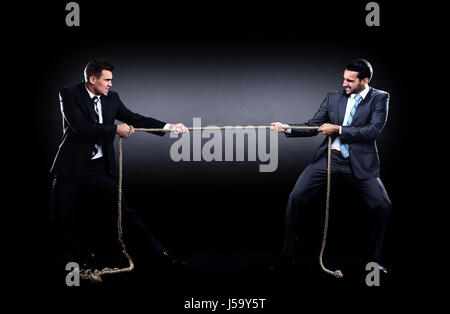 Two business men pulling rope in a competition Stock Photo - Alamy