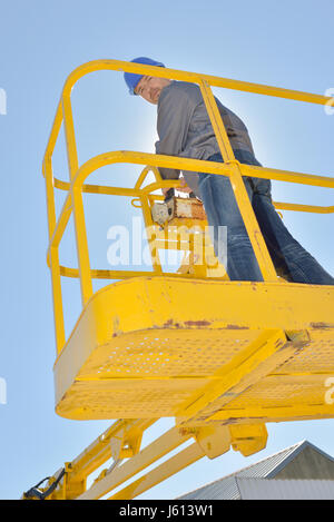 Upward view of man in cherry picker Stock Photo - Alamy