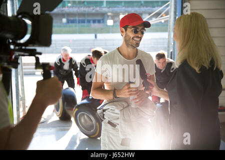 Female news reporter interviewing male race formula one driver in ...