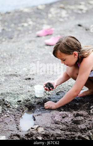 young girl digging a hole in the sand Stock Photo - Alamy