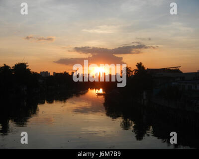 This photograph captures a sunset over the Pasig River, with views of ...