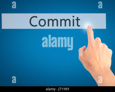 Commit - Hand pressing a button on blurred background concept ...