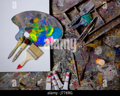 Overhead view of messy painting equipment in dirty container on table ...