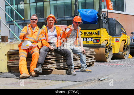 Three male construction workers taking a break from work, builders men ...