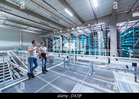 Two men in automatized high rack warehouse Stock Photo - Alamy