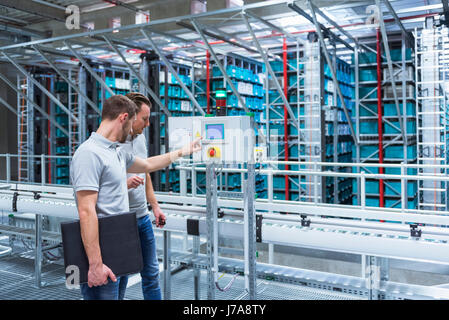 Two men in automatized high rack warehouse Stock Photo - Alamy