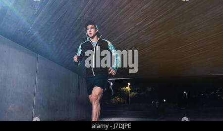 Young sportsman jogging in the night city Stock Photo - Alamy