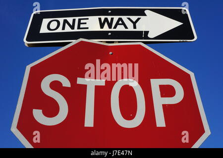 one way and no left turn signs in red black and white with out of focus ...