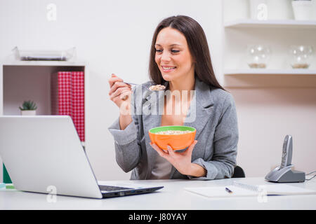 Young woman eating healthy oatmeal on grey background Stock Photo - Alamy
