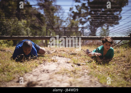 Kids crawling under the net during obstacle course training in the boot ...