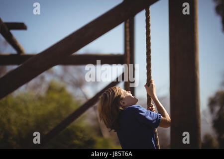 Determined girl climbing rope during obstacle course in boot camp Stock ...