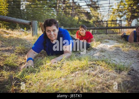 Group of fit women crawling under the net during obstacle course ...