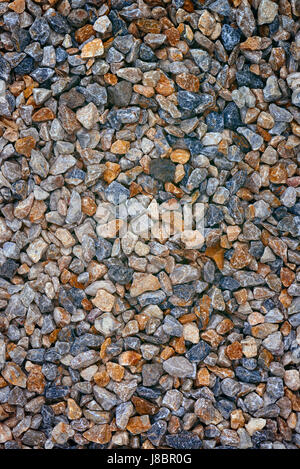 A natural view of small stones on a sandy beach under a cloudy sky ...