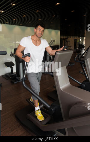 Muscular Man Doing Aerobics Elliptical Walker In Modern Fitness Center ...