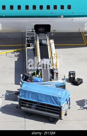 Aircraft ramp loader loading baggage to conveyor belt on airport apron ...