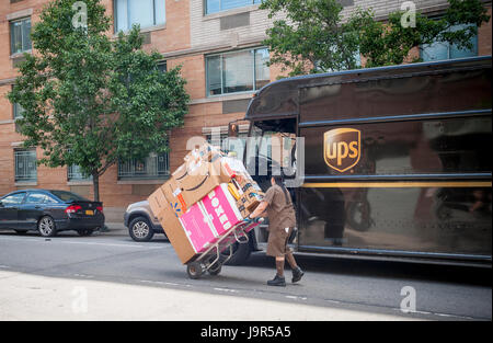 UPS (United Parcel Service) employee pulls a cart stacked high with ...