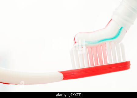Red toothbrush with multicolour toothpaste against white background ...
