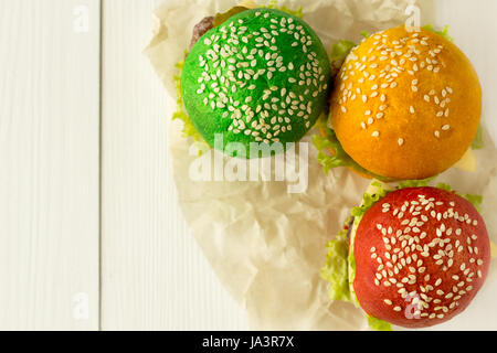 Multi colored burgers on wooden plate selective focus Stock Photo - Alamy