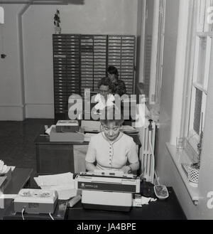 1970s, historical, three secretaries in a sparse office using audio ...