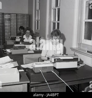 1970s, historical, three secretaries in a sparse office using audio ...