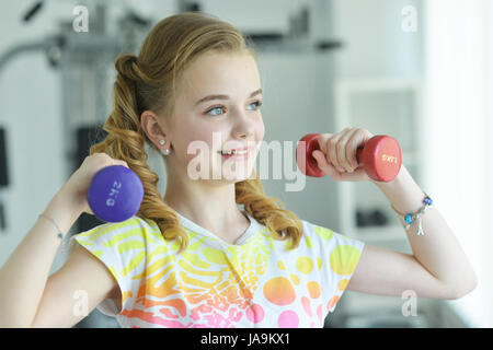 Cute little girl doing exercises with dumbbells and fit ball at home ...
