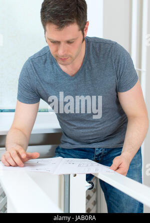 Man reading manual for self assembly furniture Stock Photo - Alamy