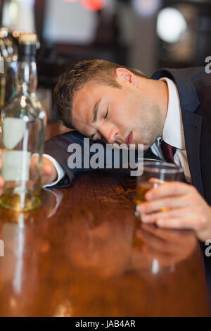 Drunk businessman slumped on bar beside cocktail at the local bar Stock ...