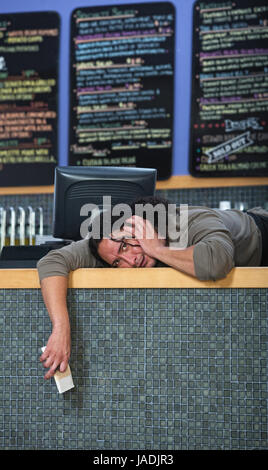 Bored man laying on counter top Stock Photo - Alamy