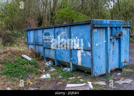 A rusty, blue waste skip standing in front of a brick building Stock ...