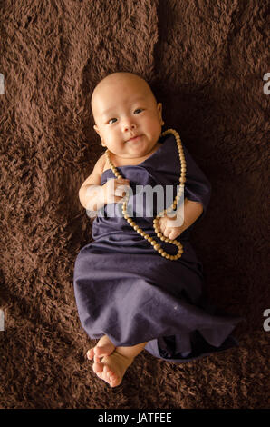 An infant baby boy with cute brown hair, laying on his back on a grey ...