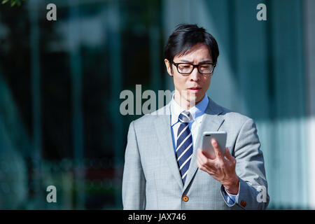 Japanese businessman with smartphone downtown Tokyo, Japan Stock Photo ...