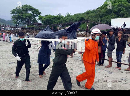 Rescuers carry the body of a victim at a village hit by a flood in ...