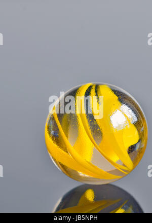 Single glass marble and reflection with a colour infused background and ...