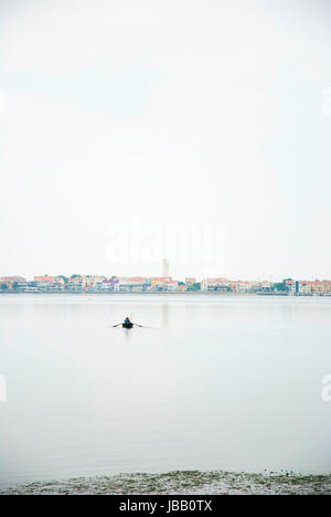 Lonely fishing boat with cityscape behind Stock Photo - Alamy