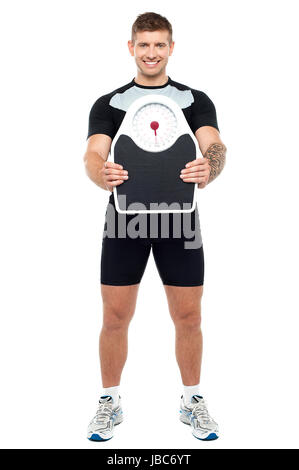Attractive athlete showing weighing scale against white background ...