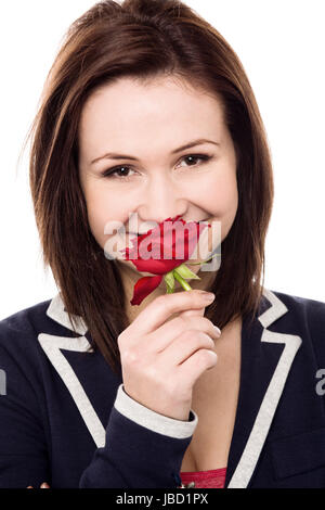 Pretty young girl smiling coyly while holding a red rose near her mouth ...