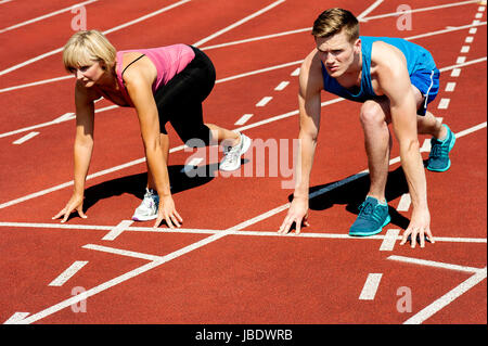 Two female athletes at starting position ready to start a race ...