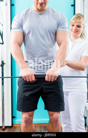 Woman doing exercises with medical bar, in a supine position. Male ...