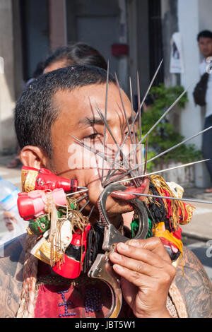 Man with cheeks pierced by skewers and handcuffs in a parade during the ...
