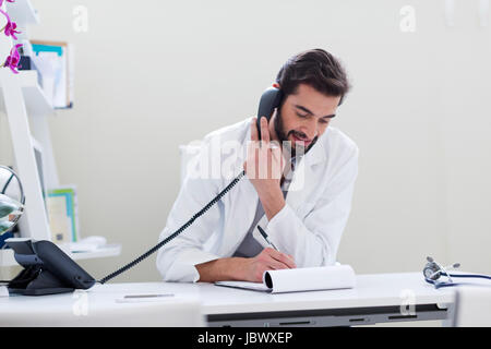Doctor at desk making telephone call Stock Photo - Alamy